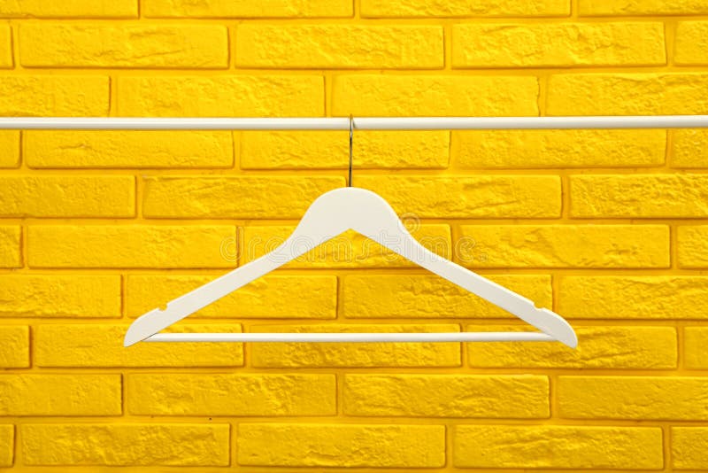 Wardrobe Rack with White Hanger Near Yellow Brick Wall Stock Photo ...