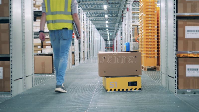 Warehouse Corridor with a Male Worker and a Robotic Machine Stock Video ...