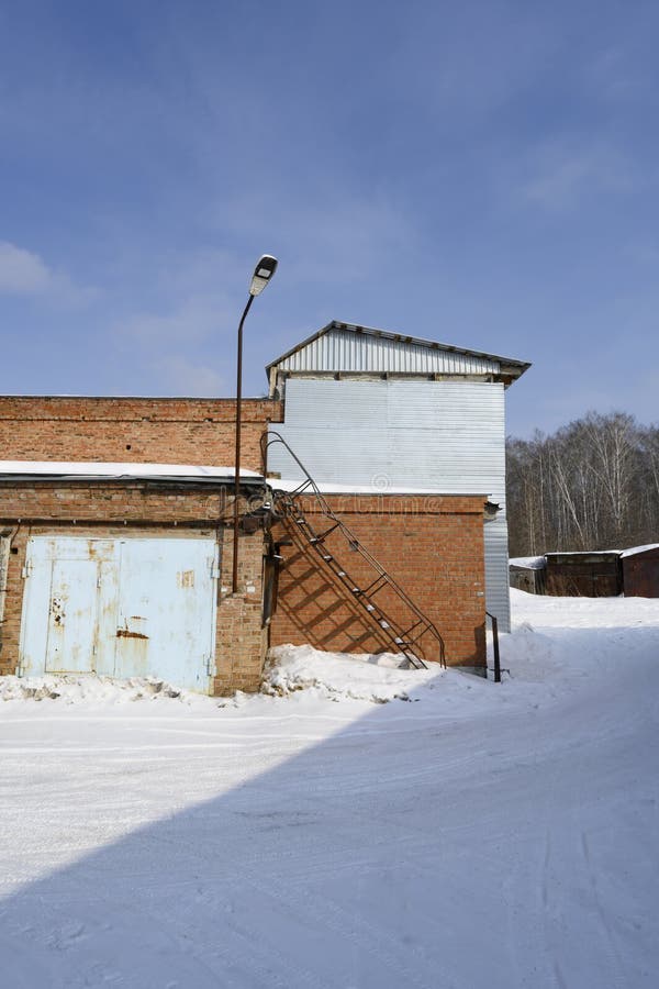 A Warehouse with a Ladder Casting a Shadow among Snowdrifts in Winter ...