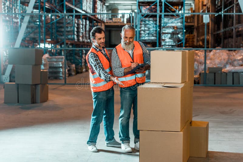 Two Male Warehouse Workers Writing on Clipboard and Looking Stock Photo ...