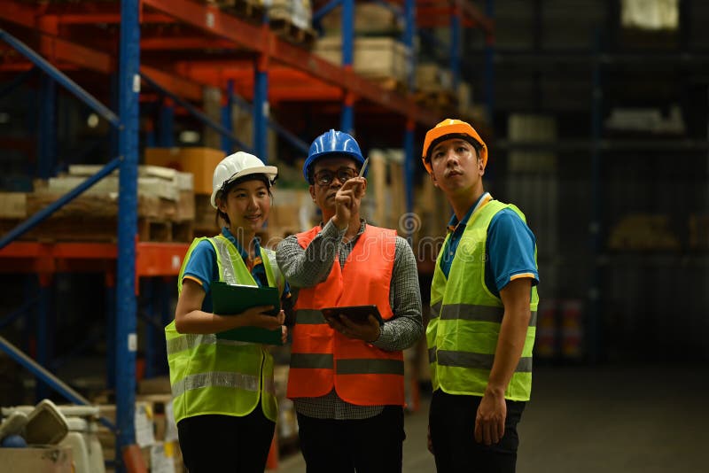 Warehouse Workers and Middle Age Manager Standing between Rows of Tall ...