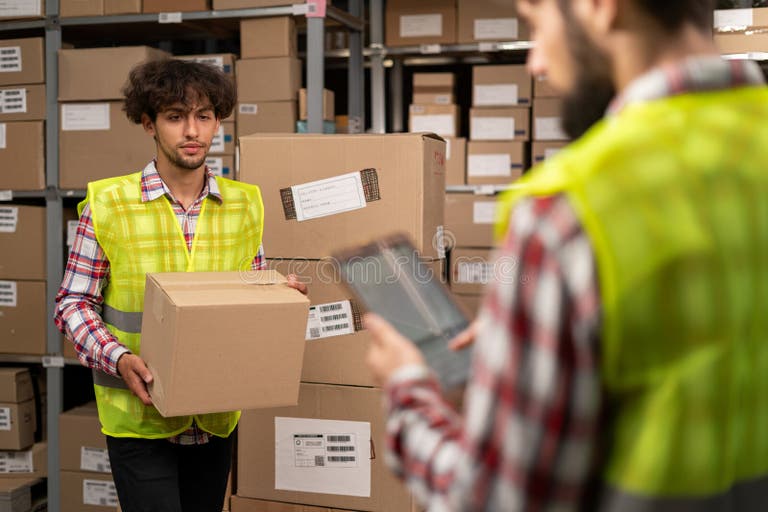 Warehouse Workers Preparing a Shipment in a Large Storehouse. Two ...