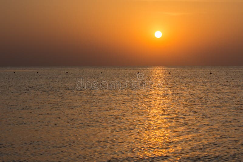 Warm Sunrise with Reflections in the Sea with Waves and Buoys Stock ...