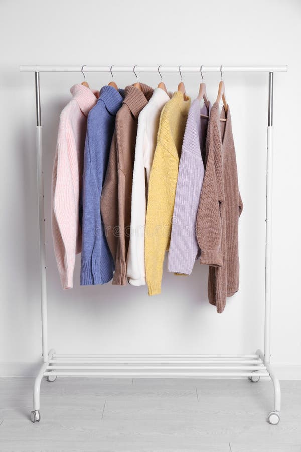 Warm Sweaters Hanging on Rack Near White Wall Stock Photo - Image of ...