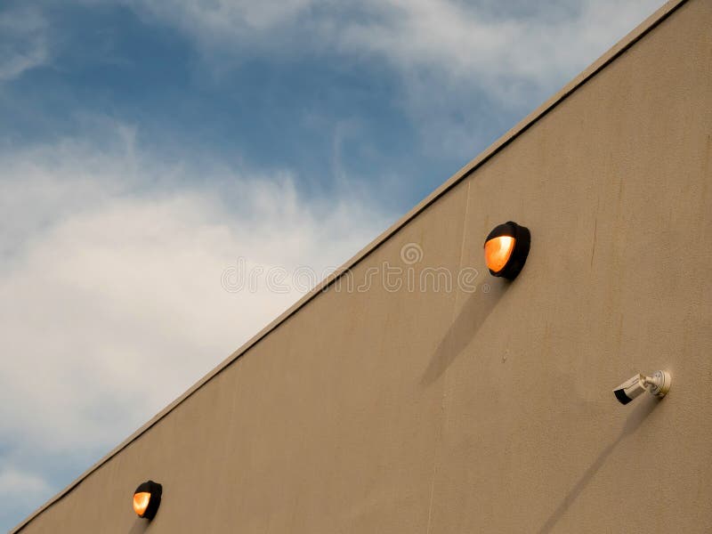 Warm Yellow Wall with CCTV Camera and Two Lights and Blue Cloudy Sky ...