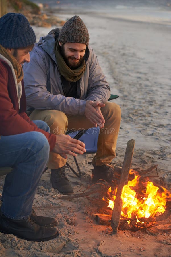 Warming Up by the Fire. Two Young Men Sitting Around a Fire on the ...