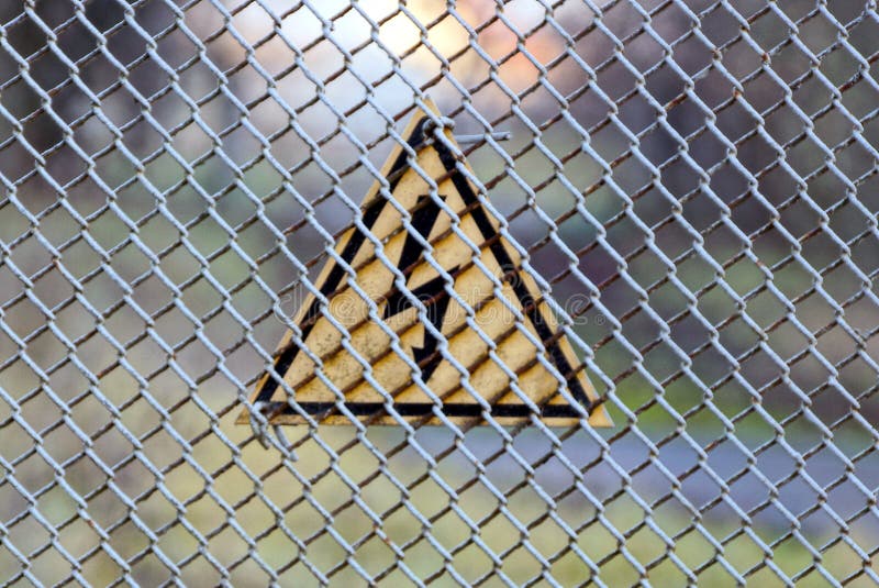 Warning Triangular Sign on a Gray Iron Shallow Grid of a Fence Stock ...