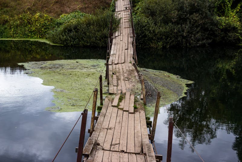 Warped and Lying on the Water Footbridge Across the River Stock Photo ...