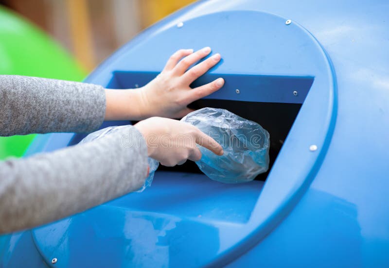 Waste Sorting. Hand Throwing Plastic Bag into Blue Recycle Bin Outdoors ...