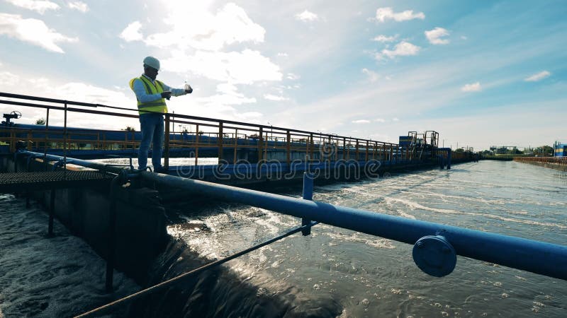 Wastewater Operator Monitoring a Sewage Treatment System Using His ...