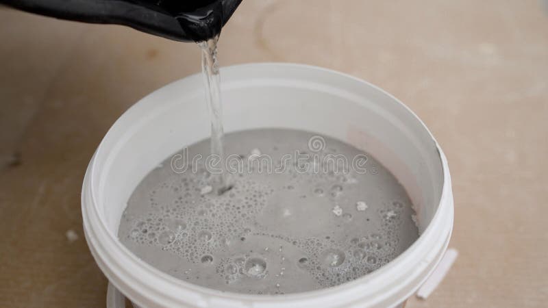 Construction Worker Pouring Water into Bucket with Gray Cement Mixture ...