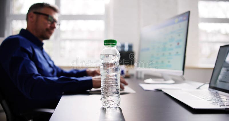 Water Bottle on Desk and Man in Background Stock Image - Image of ...