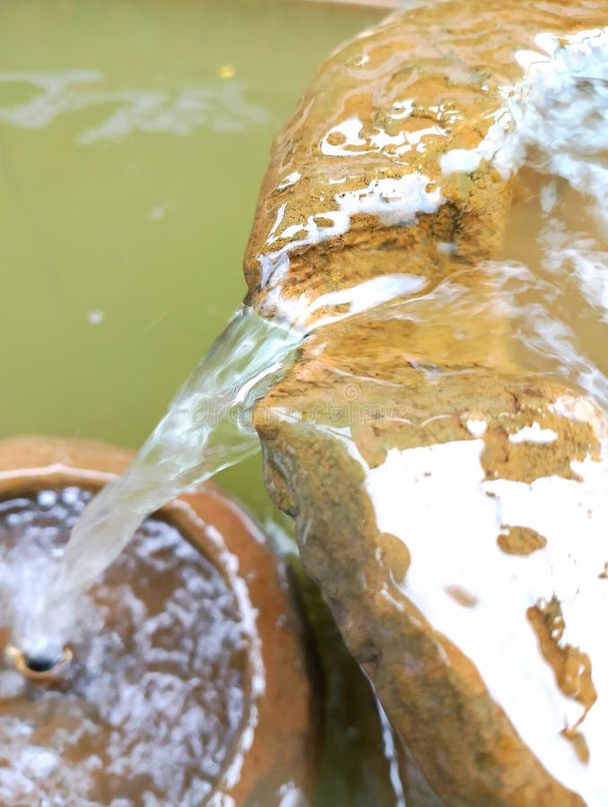 Water Flows Rapidly from a Brown Container Above into a Pool Below ...
