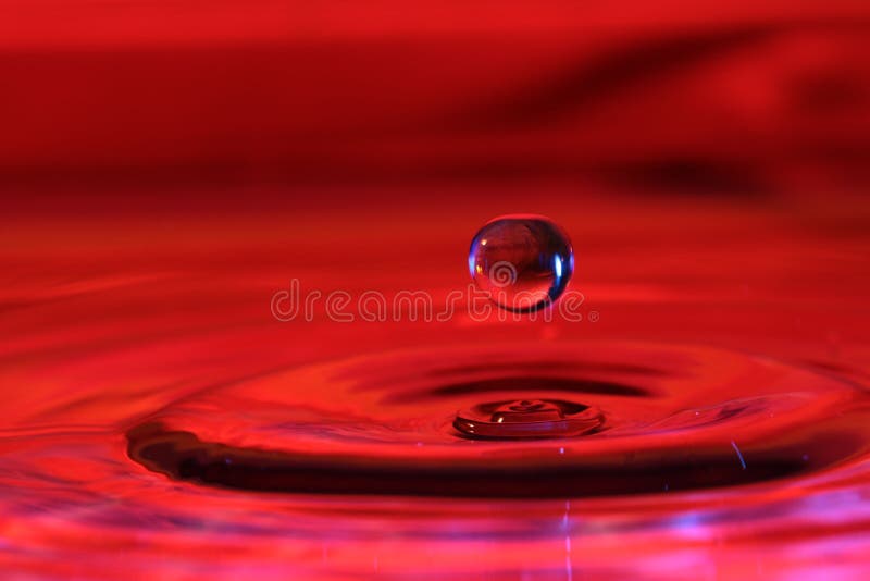 Water Drop Splashing into the Surface of Water Illuminated with Red ...