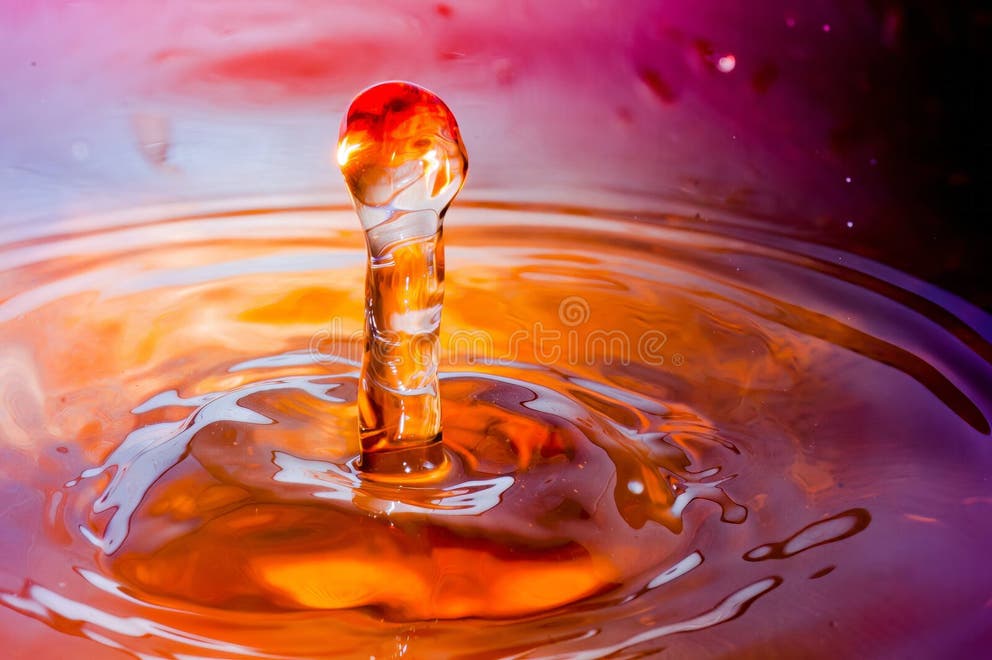 Water Droplet Causes a Splash in Multi-coloured Water Creating a Column ...