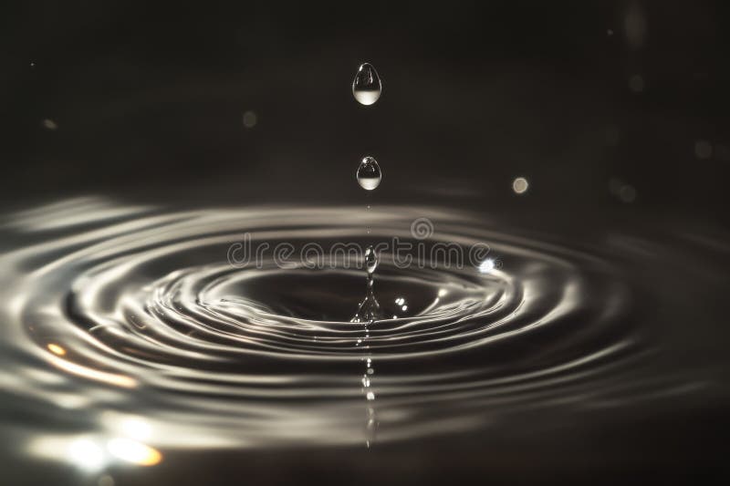 Water Droplet Creates Ripples in Still Surface Under Dim Lighting ...