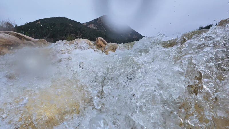 Slow Motion Waterfall Flowing between Rocks with Mountain View Stock ...