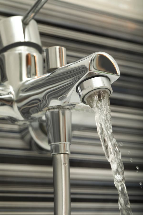 Water Flowing From Bath Tap Installed On Black And White Wall Stock