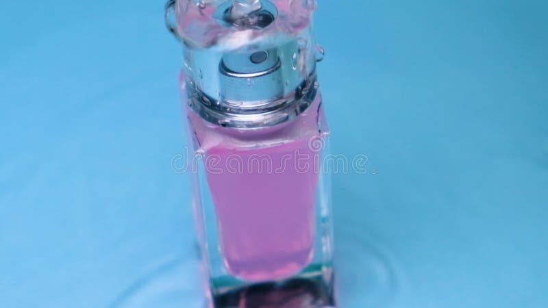Water Flows on a Glass Thin Rectangular Bottle with Pink Perfume on a ...