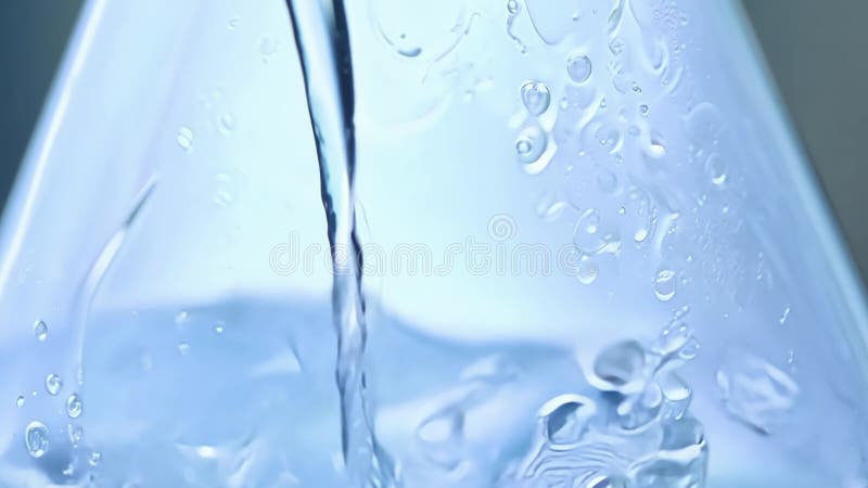 Water Pouring into a Clear Container with Bubbles in a Laboratory ...