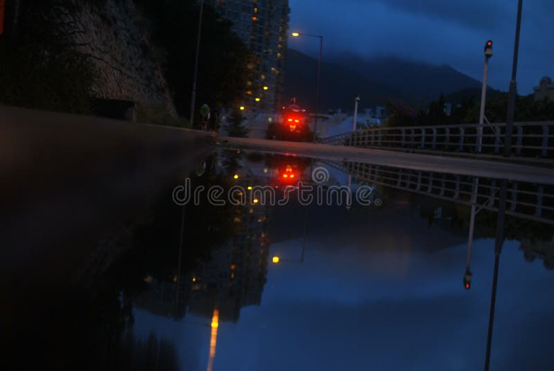 Water Reflection of a Motorcycle with Red Headlights on the Road at ...