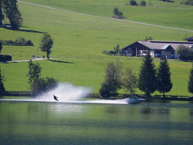 Water Skier with a Boat in Front of an Alpine Farm Backdrop with a Barn ...