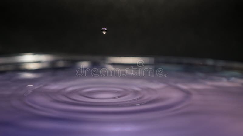 Water Splash in Colorful Background with a Drop of Water Flying from ...