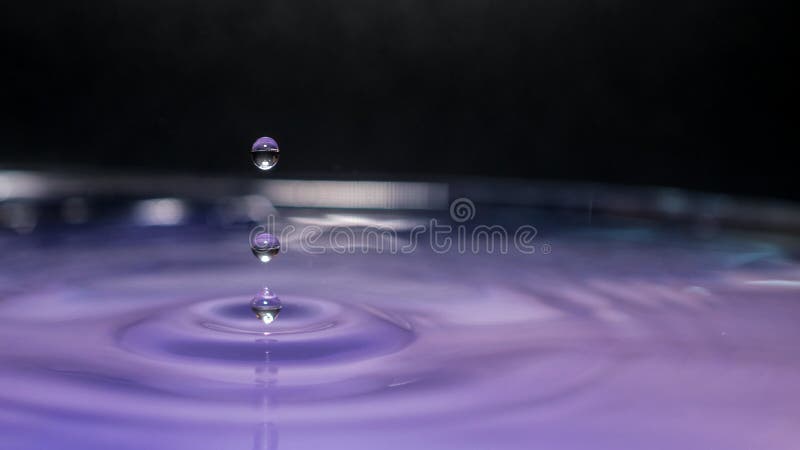 Water Splash in Colorful Background with a Drop of Water Flying from ...