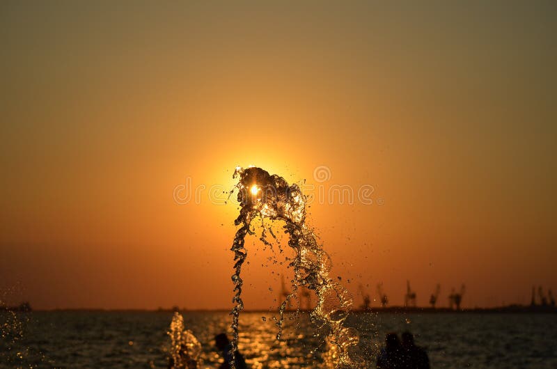 Water Splash on Sunset Colors Background with People and Cranes ...
