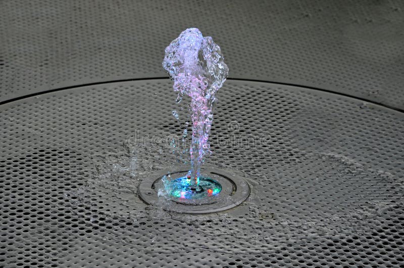 Water Sprays Backlit by Colored Lights Alternating at Night with a ...