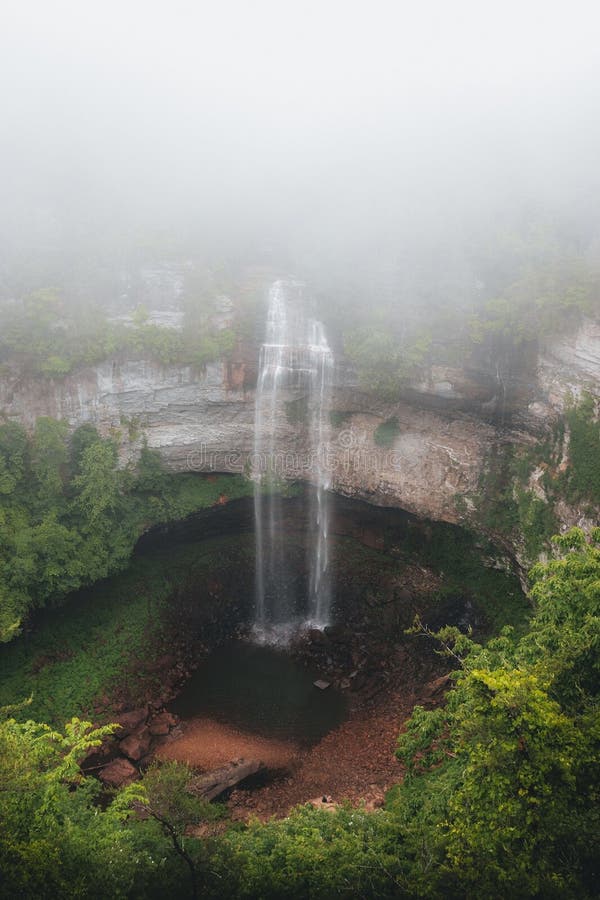 Waterfall Cascading Down a Mountainous Terrain, Surrounded by Mist ...