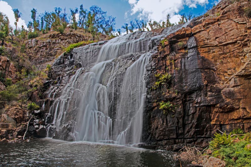 Waterfall Cascading Down Rugged Cliffs Surrounded by Lush Greenery ...