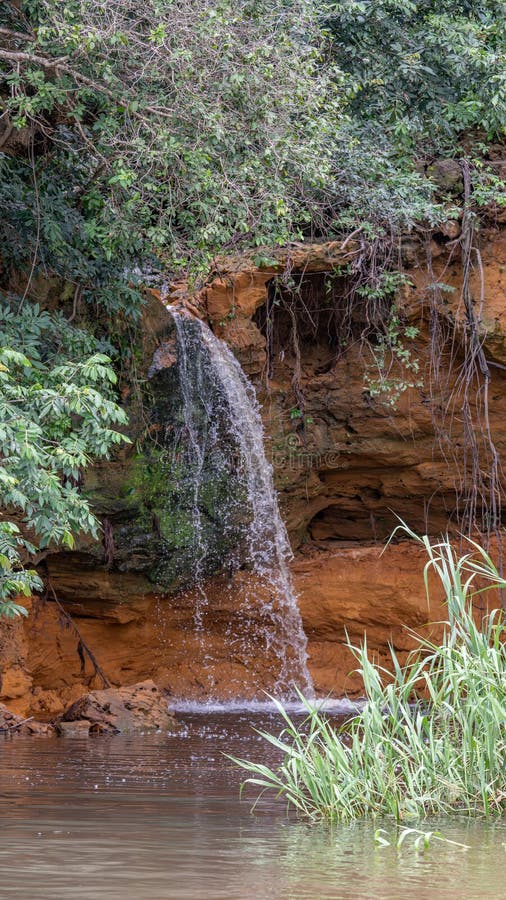 A Waterfall is Flowing Over a Cliff Face into the Water Stock Photo ...
