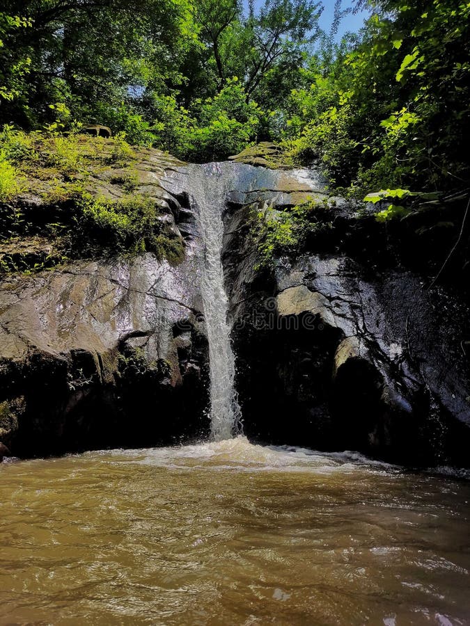 A Waterfall Casing Down a Rock Face into a River Stock Photo - Image of ...