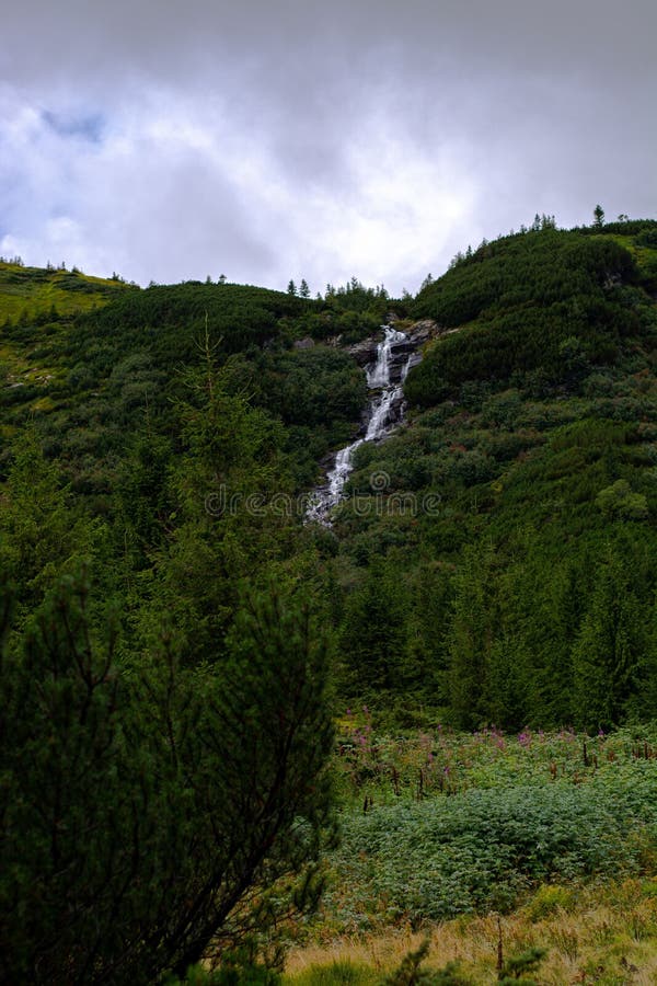 Waterfall Coming Down from a High Greenery Mountain Against Cloudy Sky ...