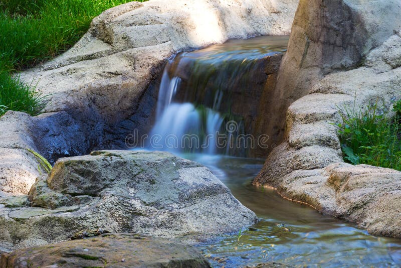 Waterfall on the Creek Flowing through Green Grass Stock Photo - Image ...