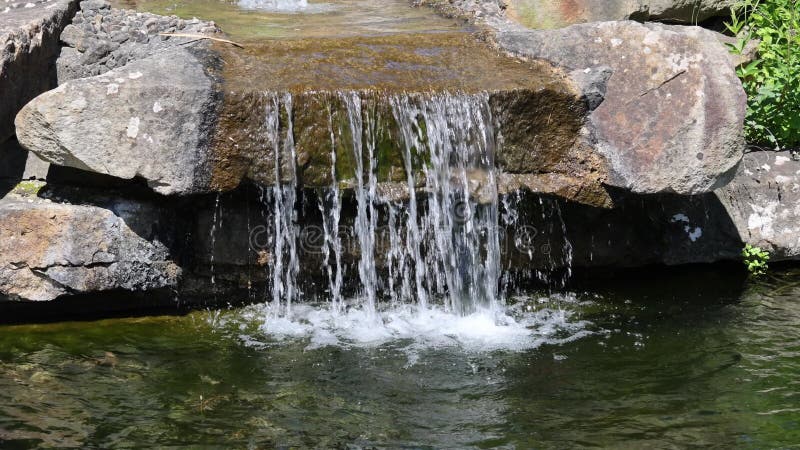 A Waterfall is Flowing Over a Rock Ledge. the Water is Clear and the ...