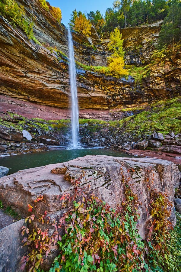 Waterfall Pouring Over Layered Cliffs from Below with Rocks with Red ...