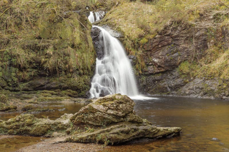 Waterfall Pouring into a Pool Behind a Rock Stock Photo - Image of ...