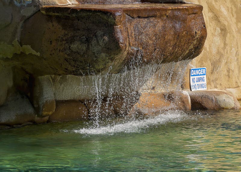 A Waterfall at a Resort Swimming Pool with a Warning Sign Stock Image ...