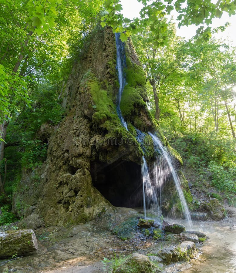 Waterfall on Stream Flowing Along Rock with Two Grottoes, Backlit Stock ...