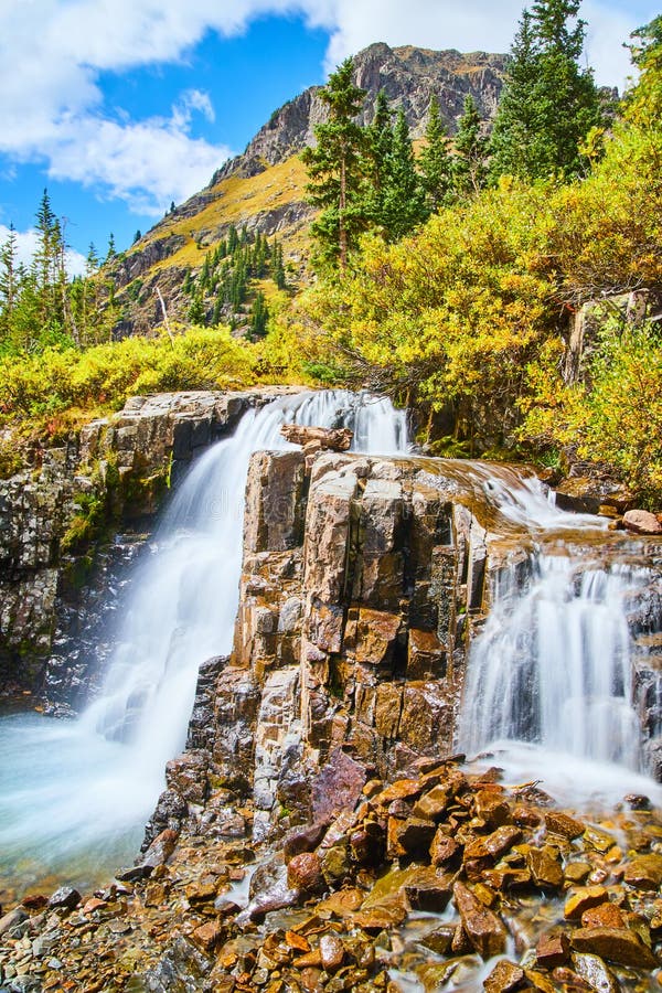 Waterfalls Over Chunks of Rocks in the Early Fall with Mountain in the ...