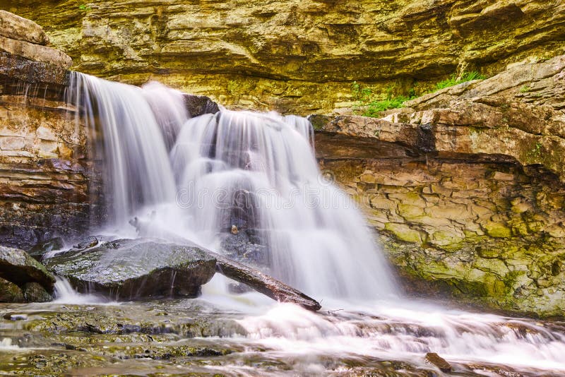 Waterfalls Over Rocky Cliffs Onto Boulders and Log Stock Image - Image ...