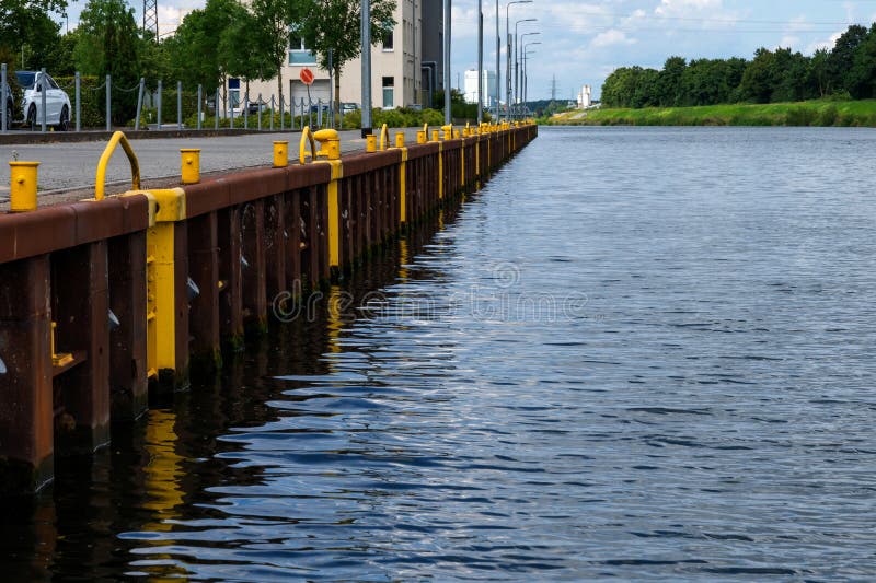 Waterfront Dock with Yellow Bollards Lining the Edge, Reflecting in the ...