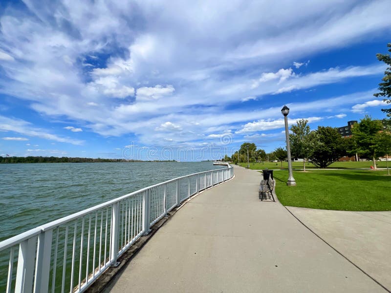 Waterfront Park with Path Along Shoreline Under a Cloudy Blue Sky ...