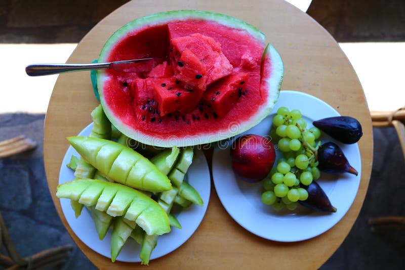 Watermelon, Melon and Grapes on Three Plates on a Wooden Table Stock ...