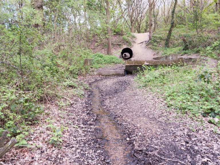 A Waterway Coming Out of a Pipe Going Underground on a Hill Deep Stock ...