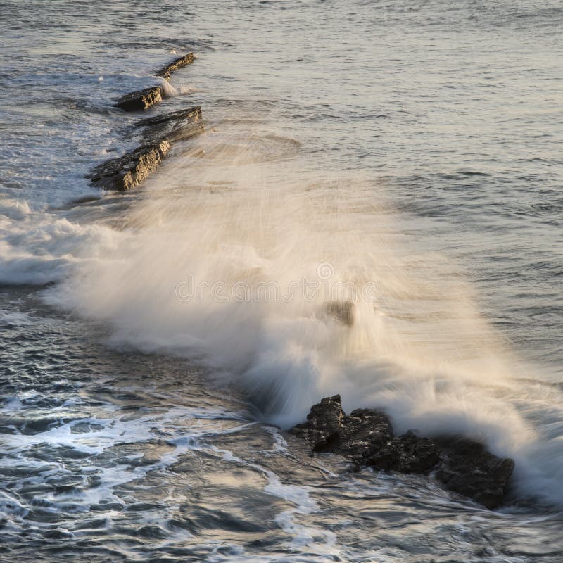 Wave Crashing Over Rocks in Ocean at Sunrise with Long Exposure Stock ...