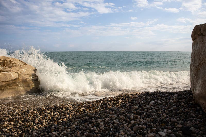 A Wave Effectively Smashing Against a Large Stone Stock Photo - Image ...