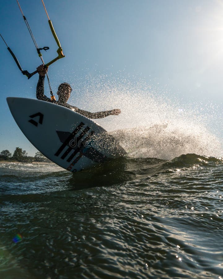 Wave Kitesurfer Doing a Turn in a Wave and Splashing Water is Backlit ...